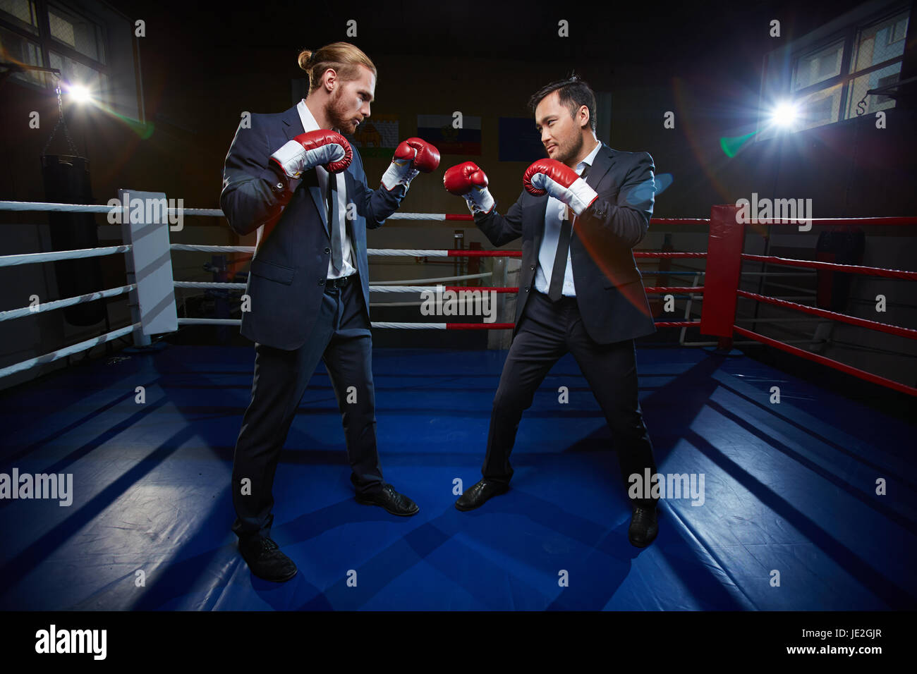 Professional businessmen in suits and boxing gloves standing opposite ...