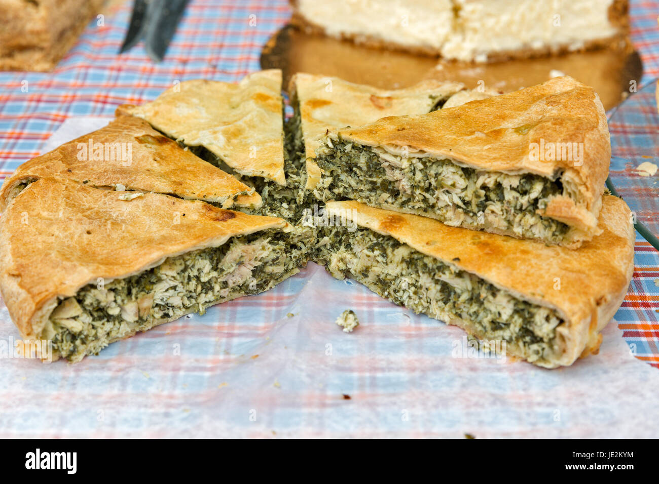 Savory round pie with spinach and meat closeup outdoor, street food ...