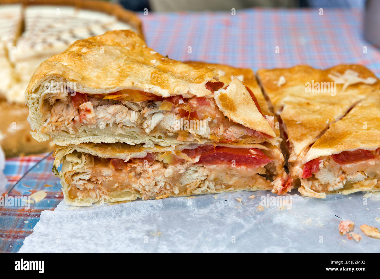 Savory round pie with meat, tomato and cheese closeup outdoor, street ...