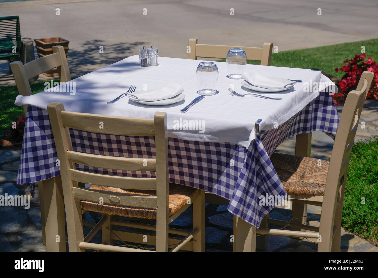 A Greek traditional tavern with white tablecloth, wooden chairs, dishes ...