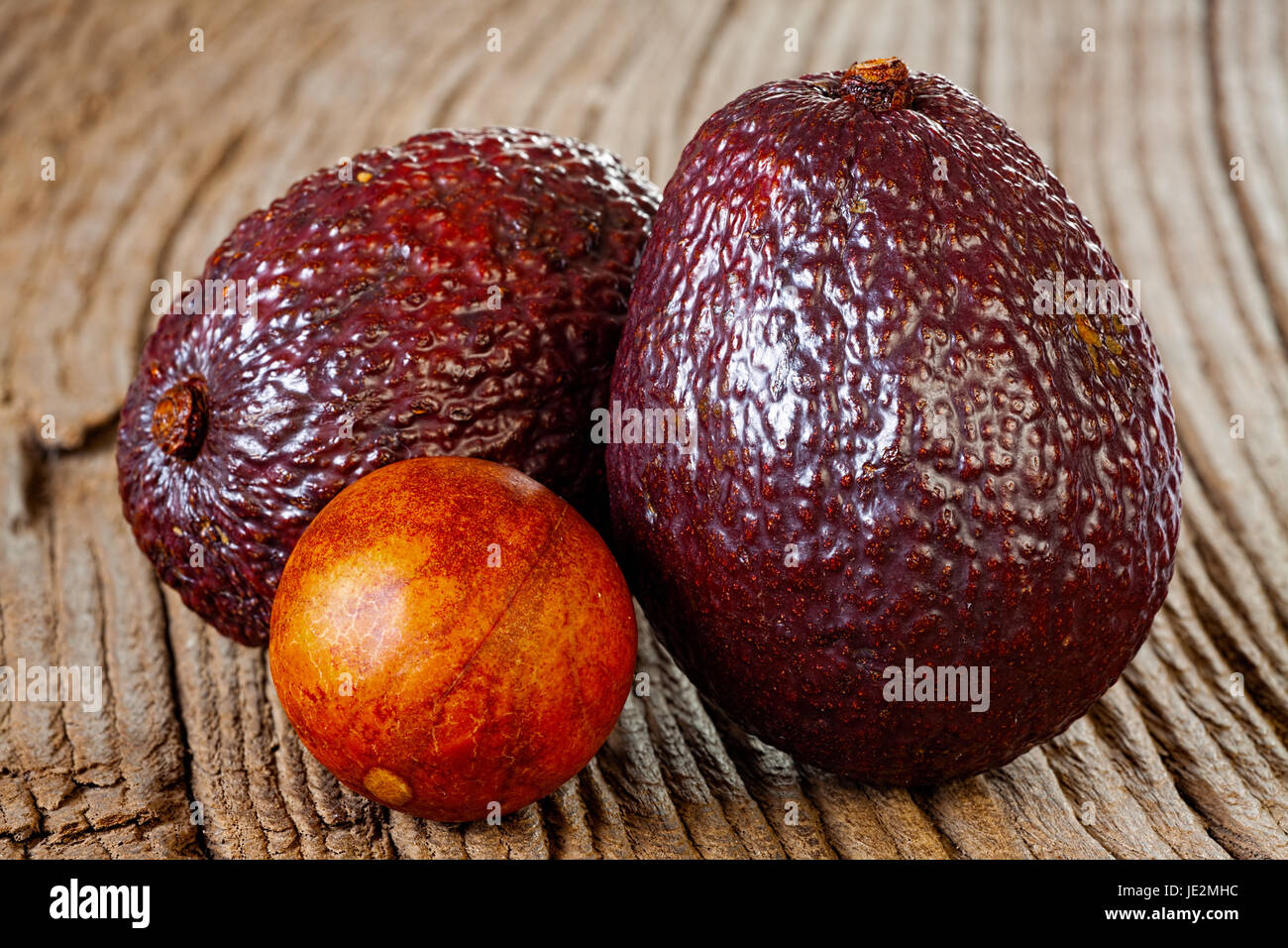 Close up view of two ripe avocados and avocado stone on an old rustic ...