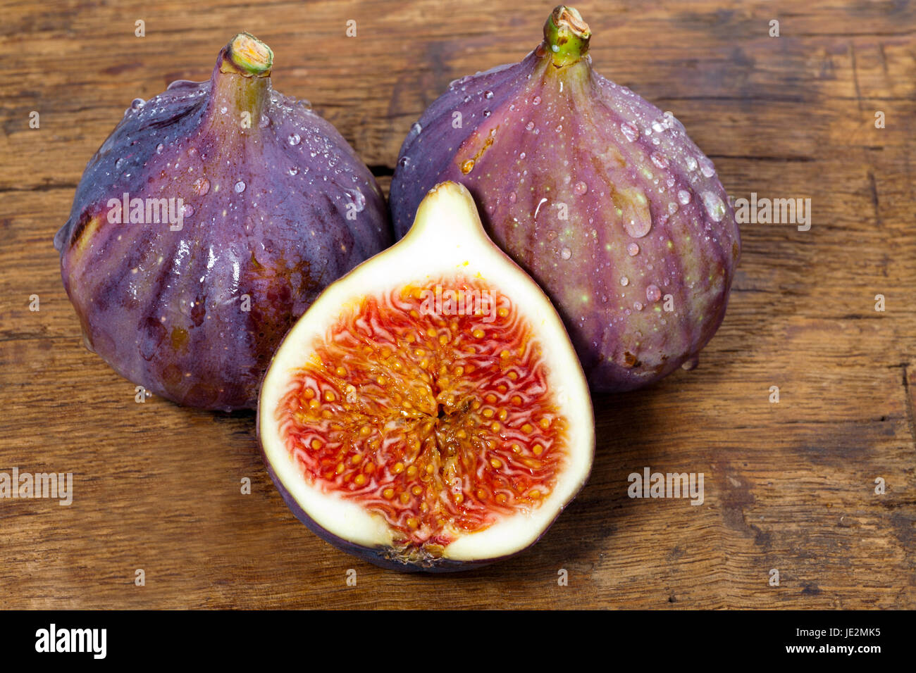 Two whole and one half fresh figs on old rustic wooden board Stock ...