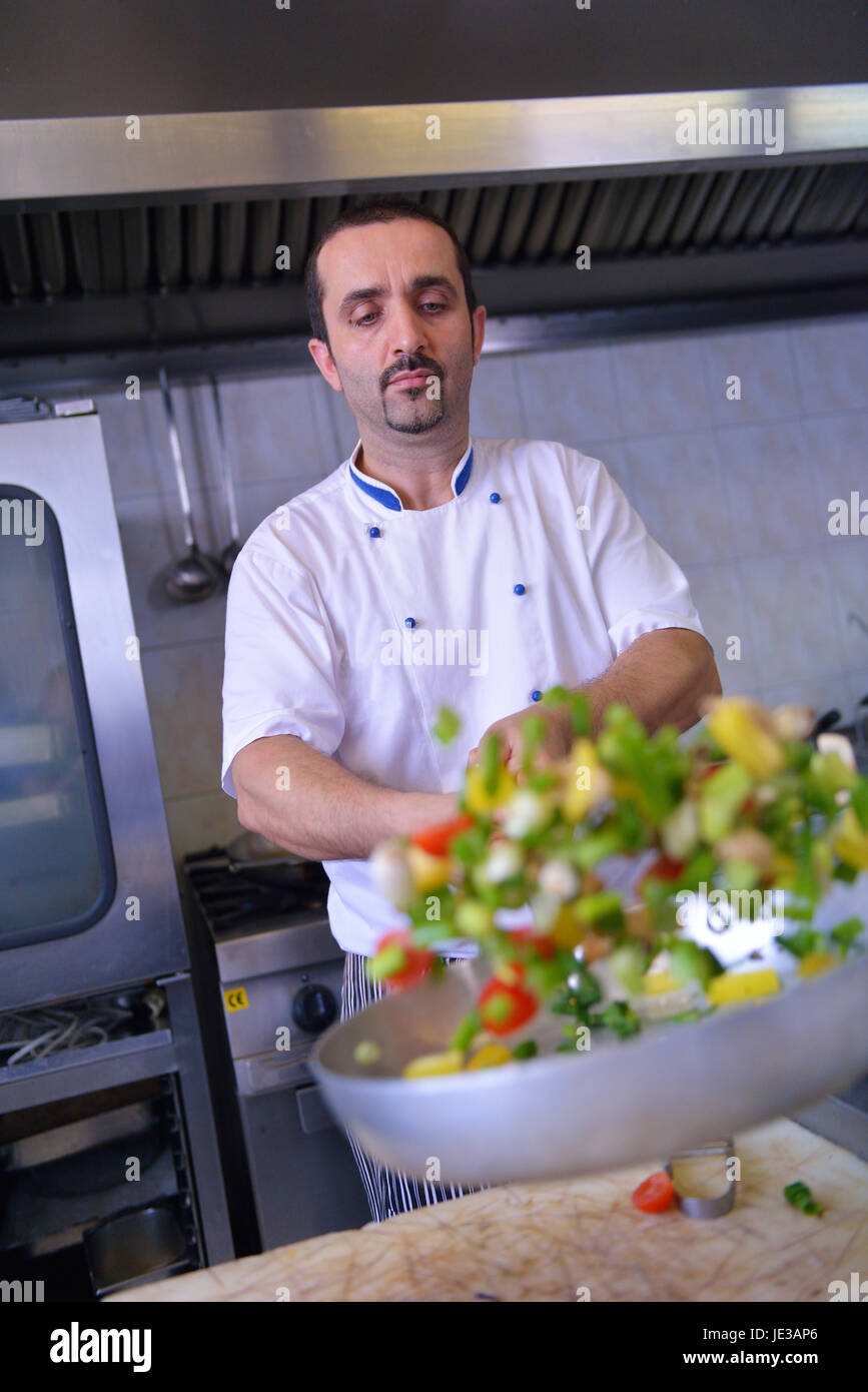 Handsome chef dressed in white uniform decorating pasta salad and ...