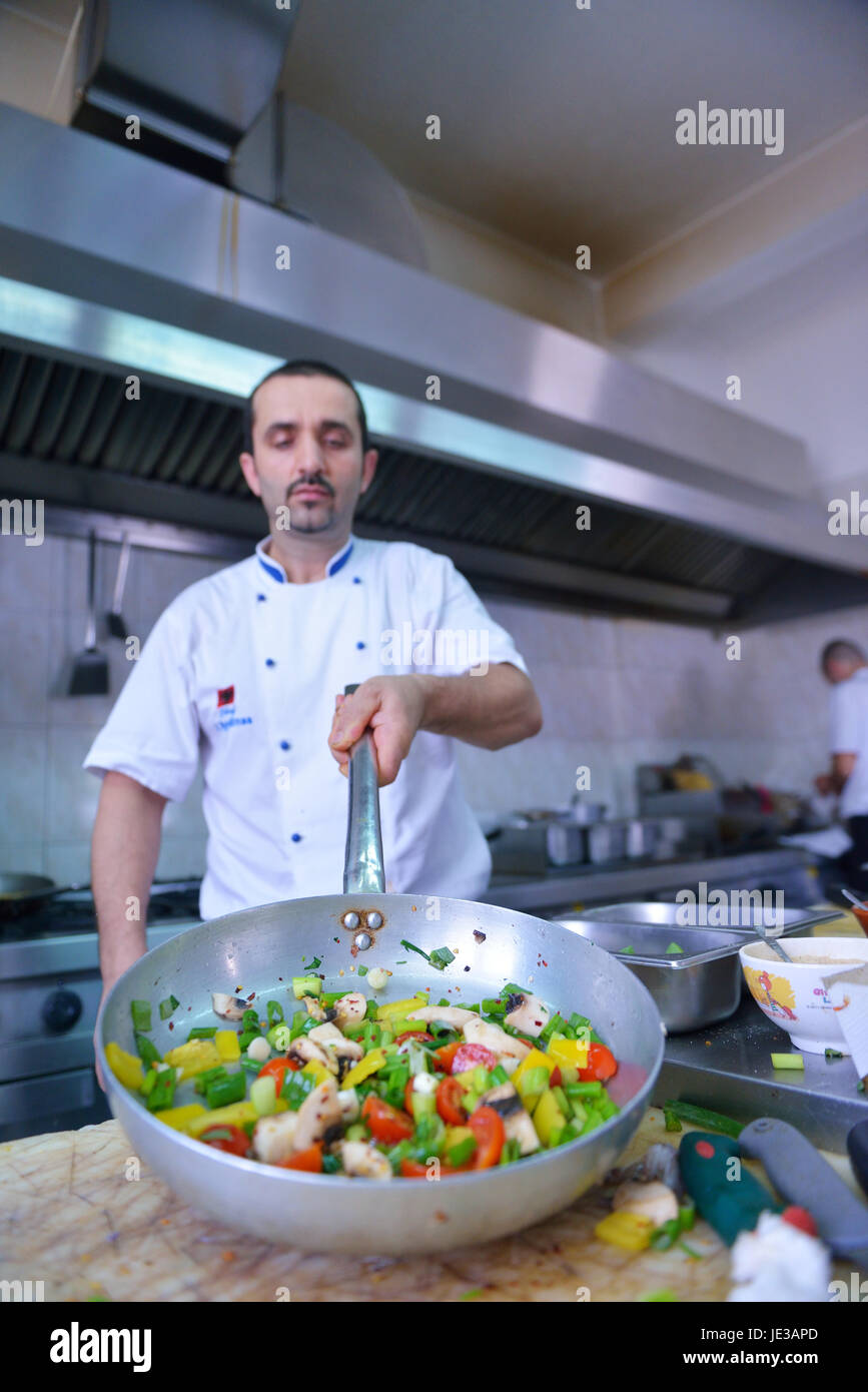 Handsome chef dressed in white uniform decorating pasta salad and ...