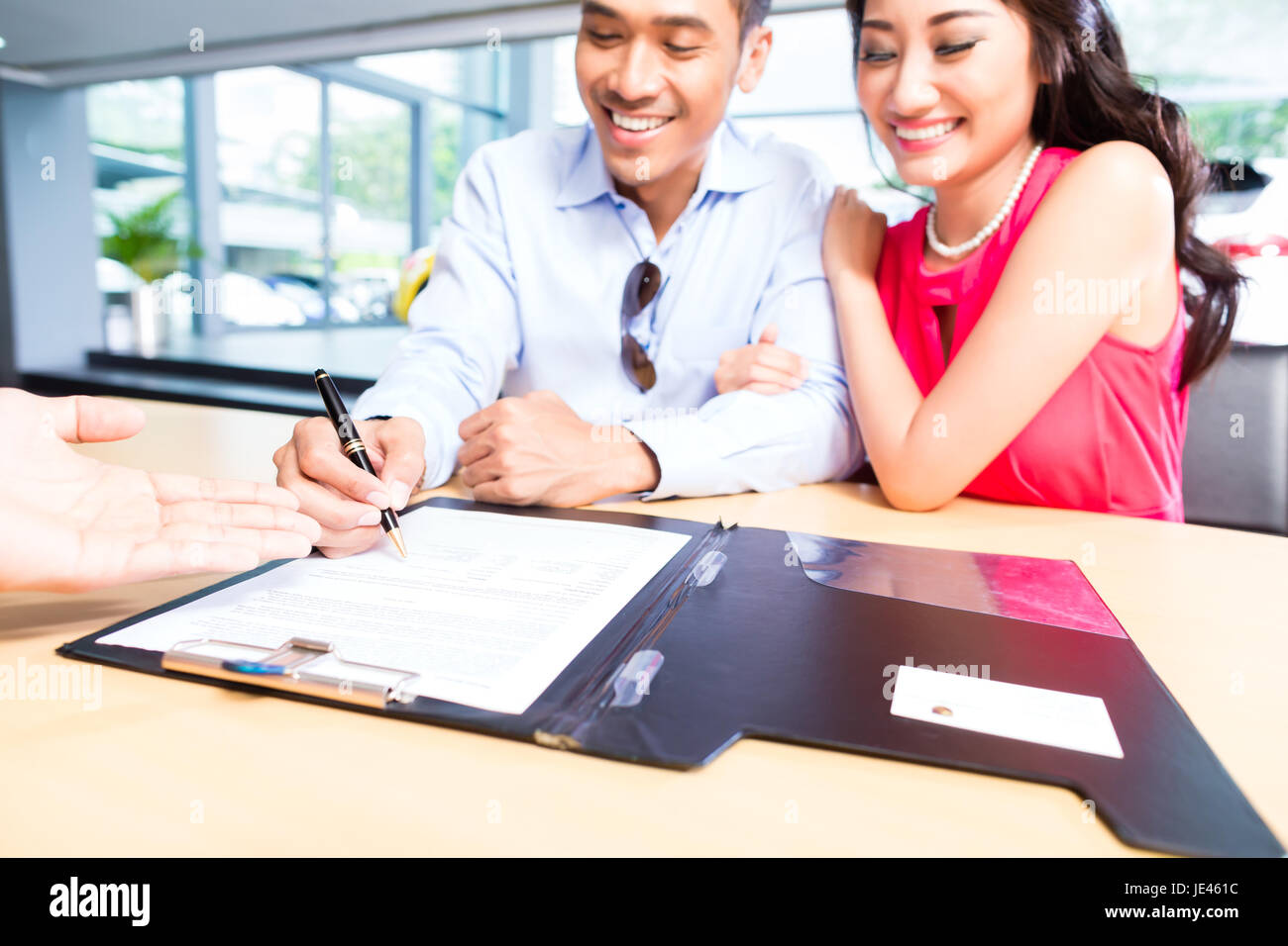 Asian Couple signing sales contract for car at dealership Stock Photo ...