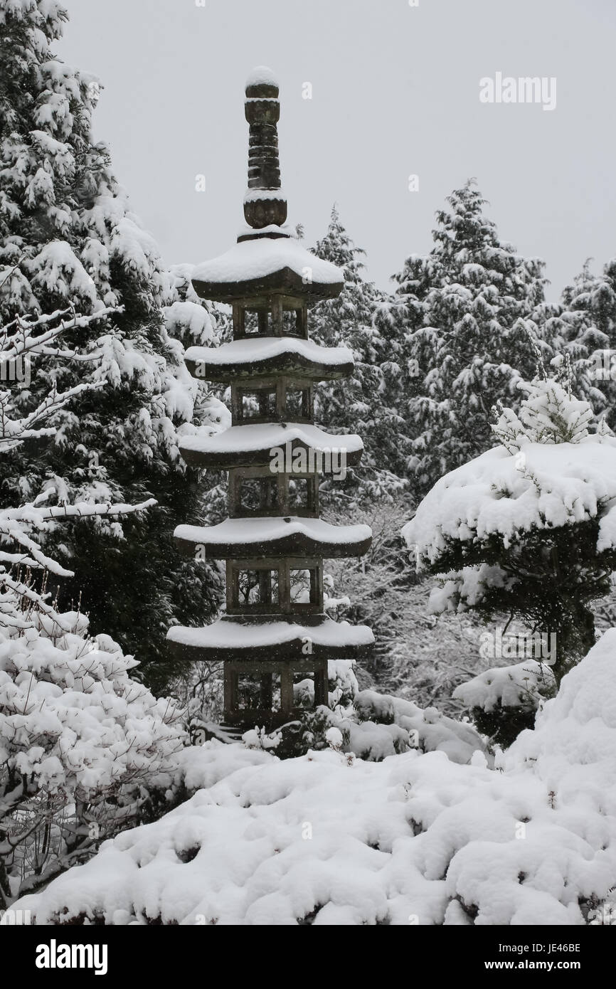 Concrete pagoda garden feature covered with late spring snow in Hakone ...