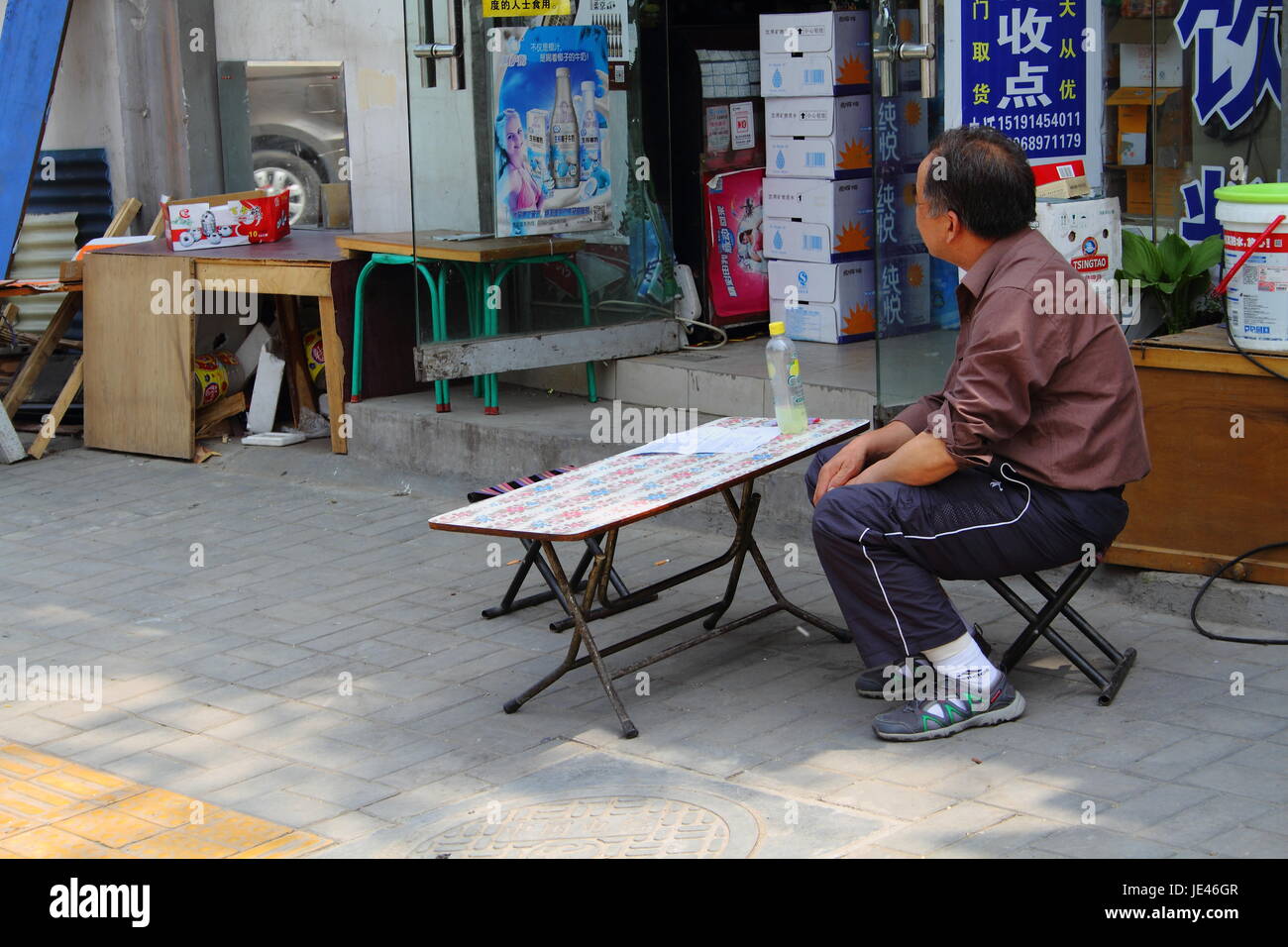 Xi'an China a shopkeeper sits outside his small shop in the city Stock ...