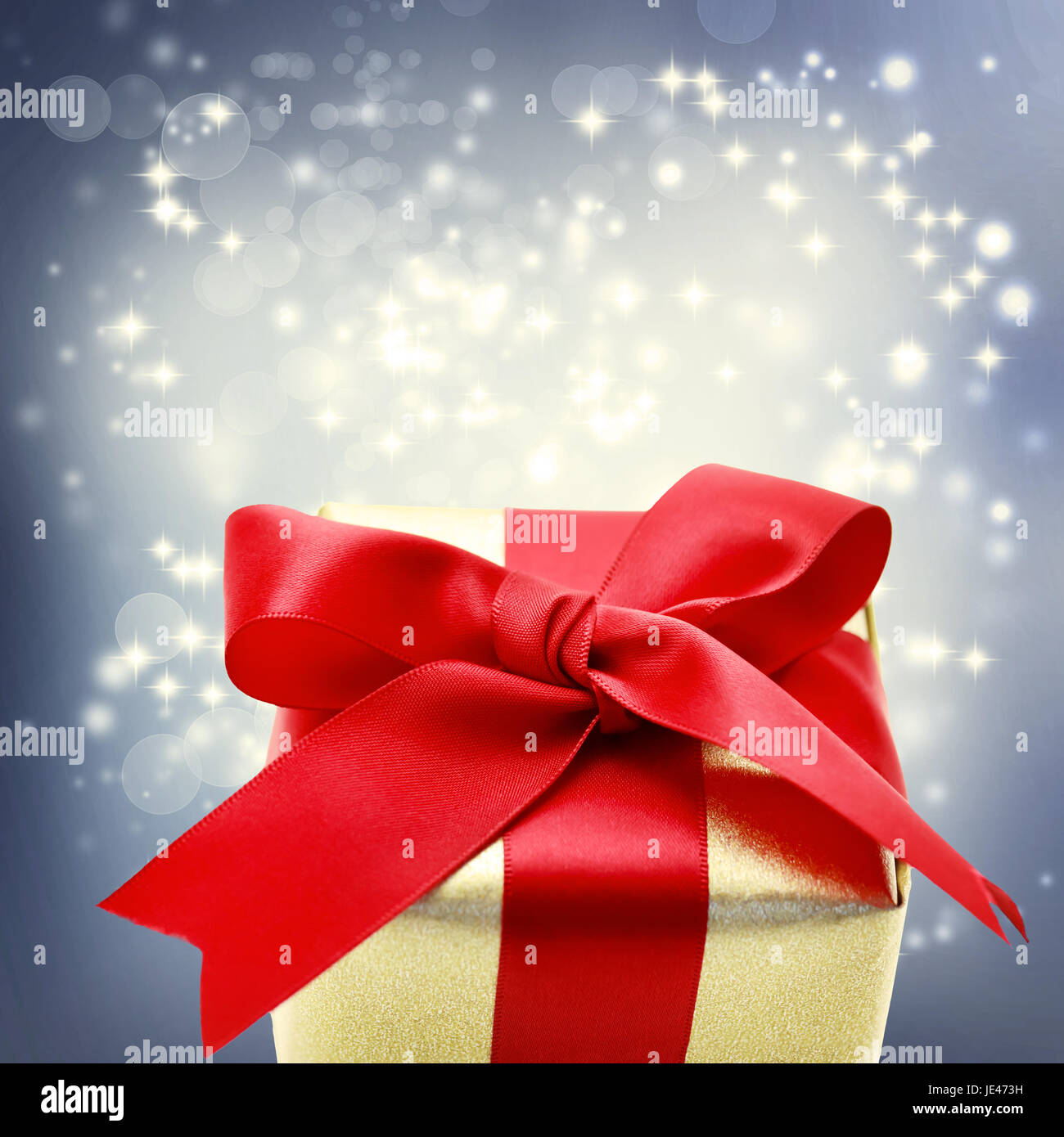 Golden present box with big red ribbon for Christmas on a shinning ...