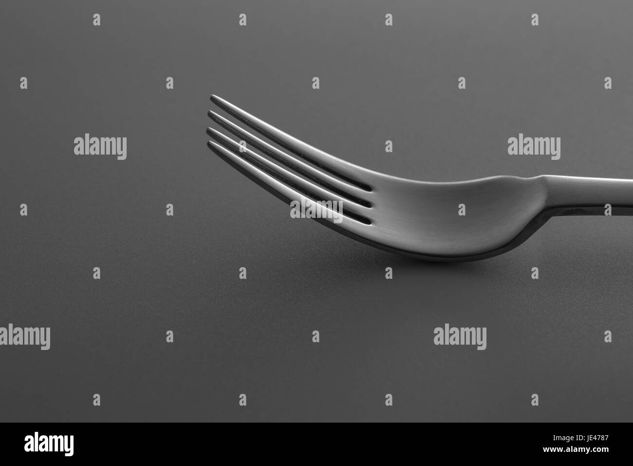 Close-up shot of metallic fork lying down on dark gray surface ...