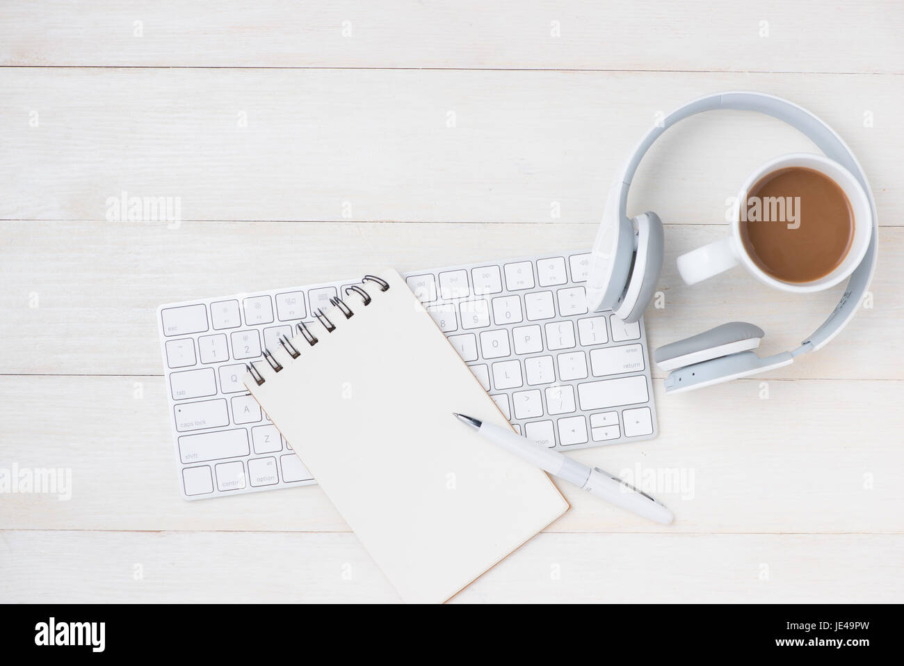 Notepad and computer keyboard on white table with headphone. View from ...