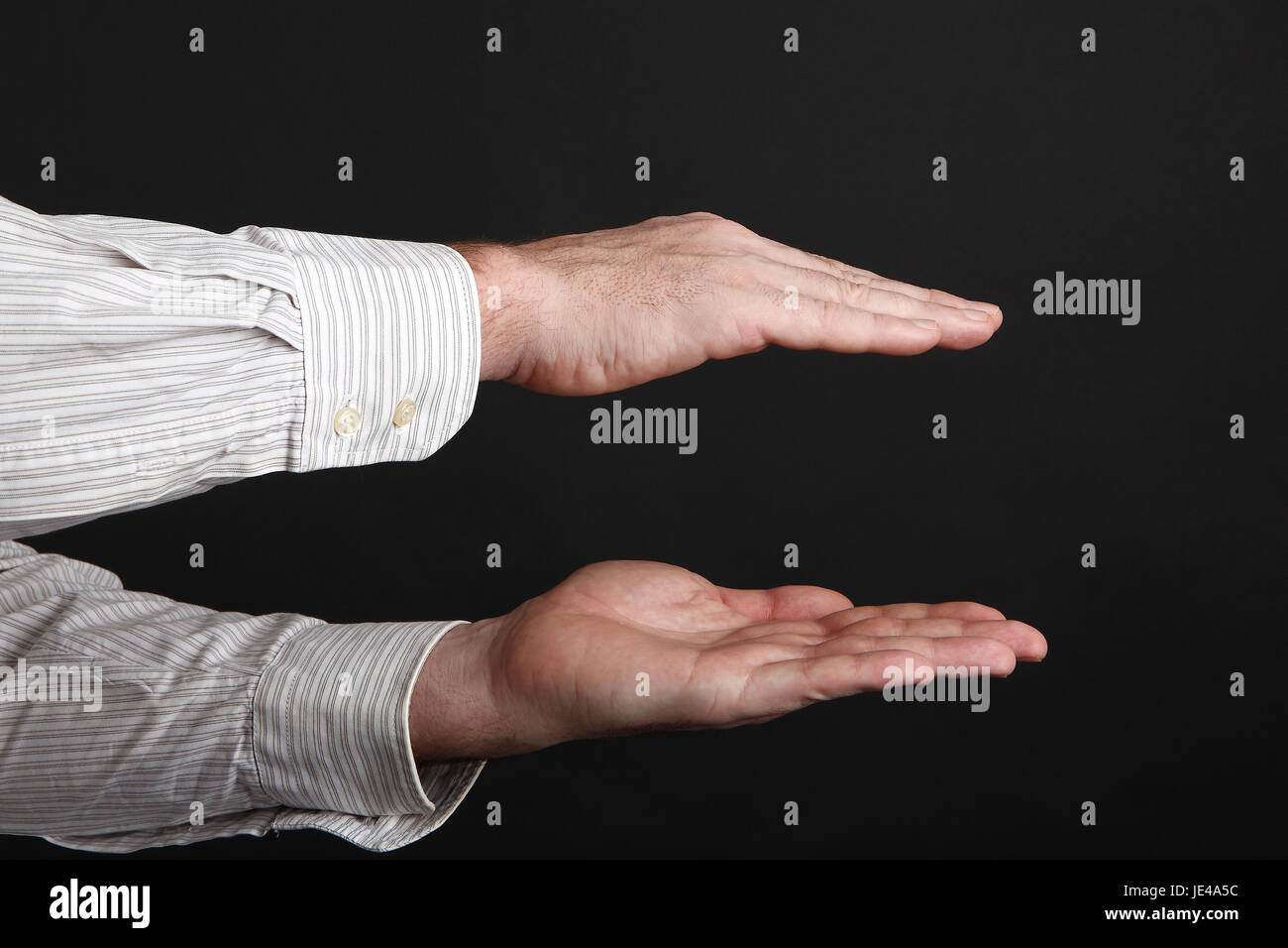 Caucasian male hands protect something in front of a black background ...