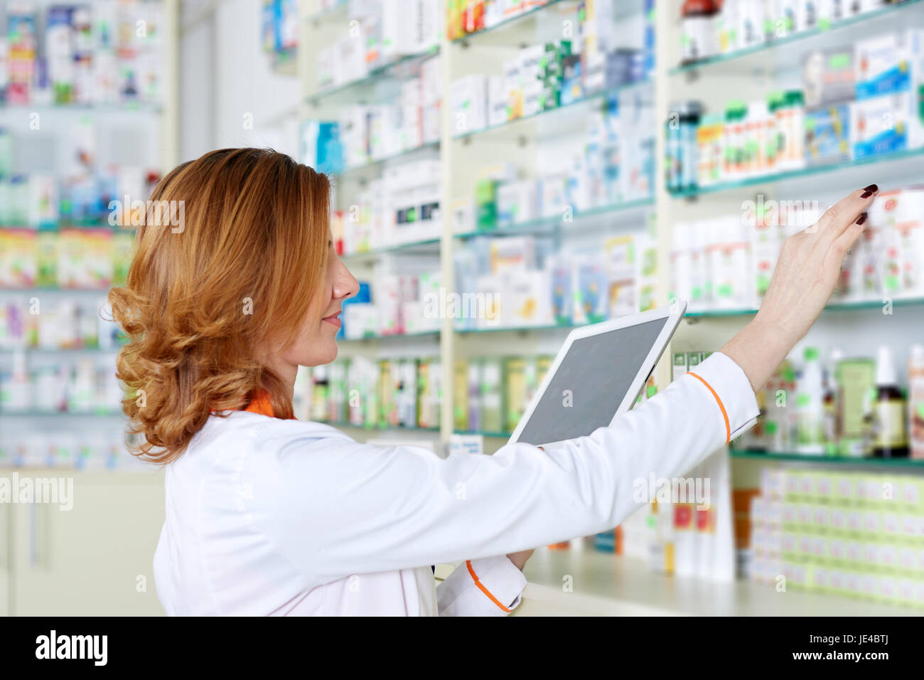 Pharmacist checking her stock of medicine with a tablet Stock Photo - Alamy