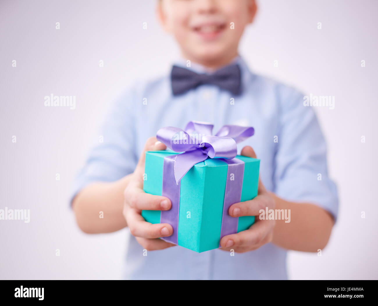 Blue package with lilac ribbon in hands of a boy Stock Photo - Alamy