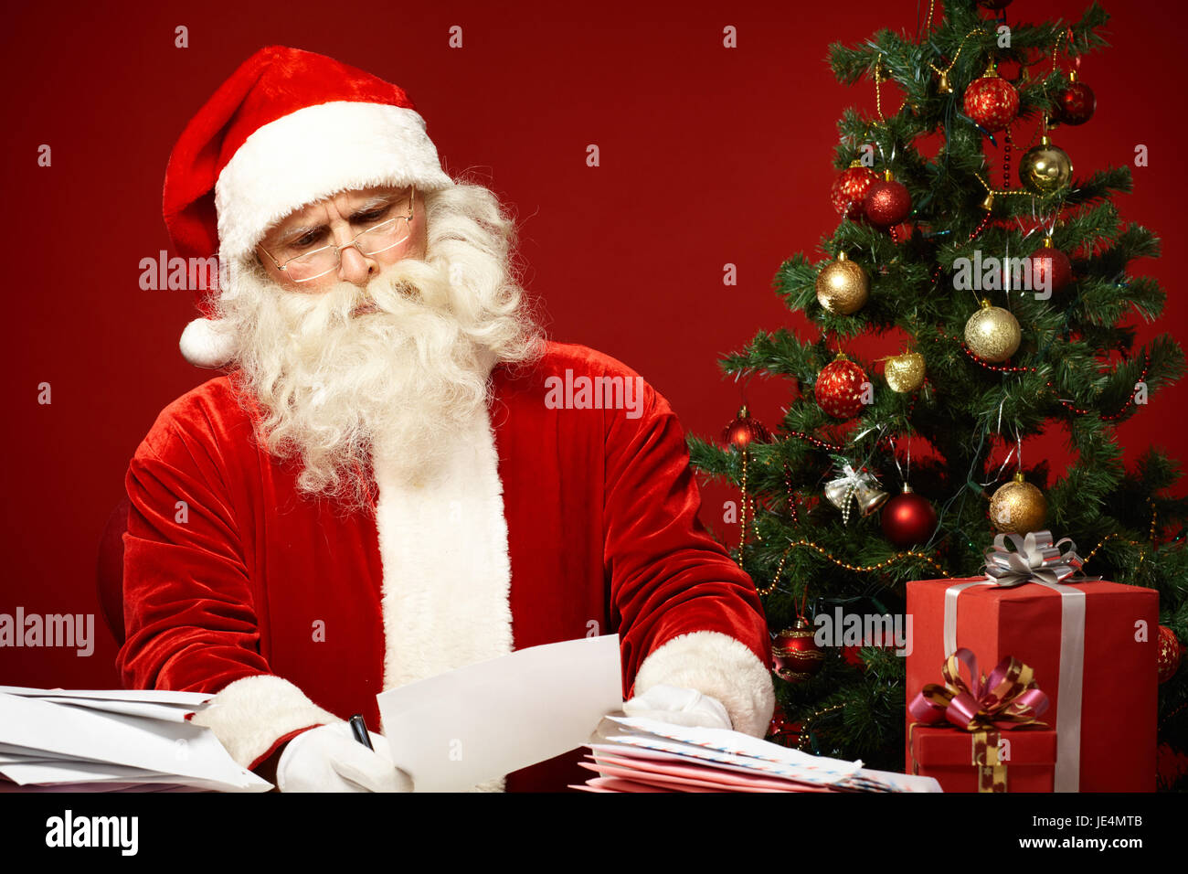 Portrait of confused Santa Claus reading letter Stock Photo - Alamy