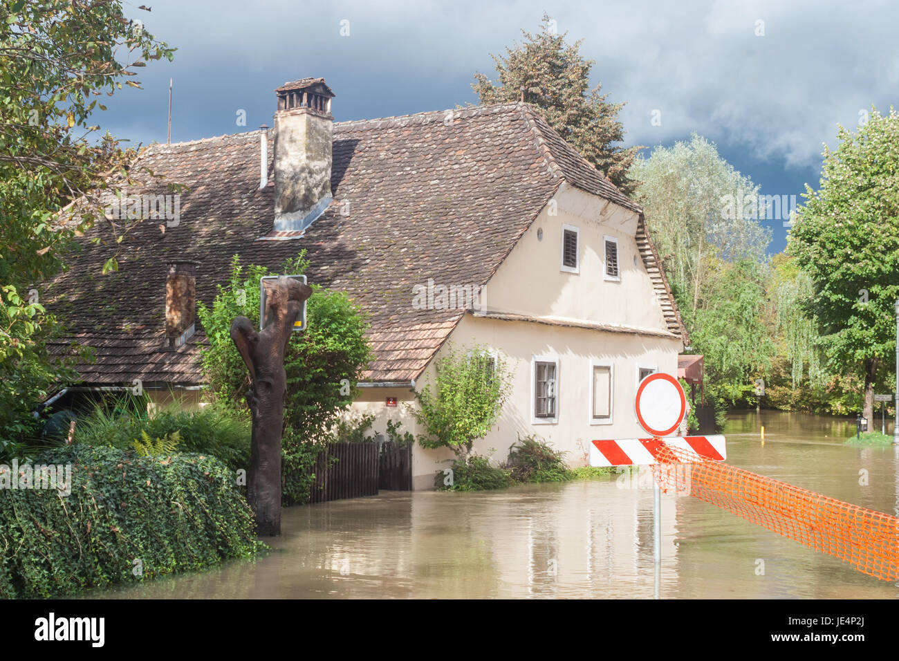 Rural village houses in floodwater. Road with the river overflown with ...
