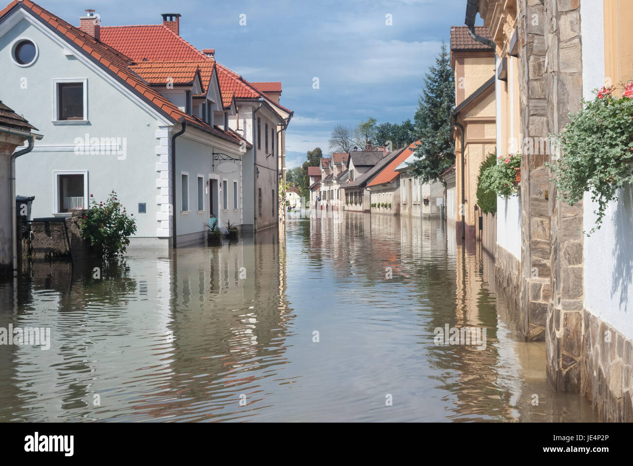 Rural village houses in floodwater. Road with the river overflown with ...