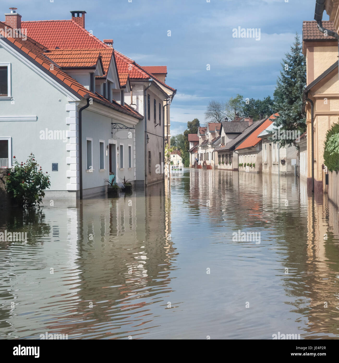 Rural village houses in floodwater. Road with the river overflown with ...