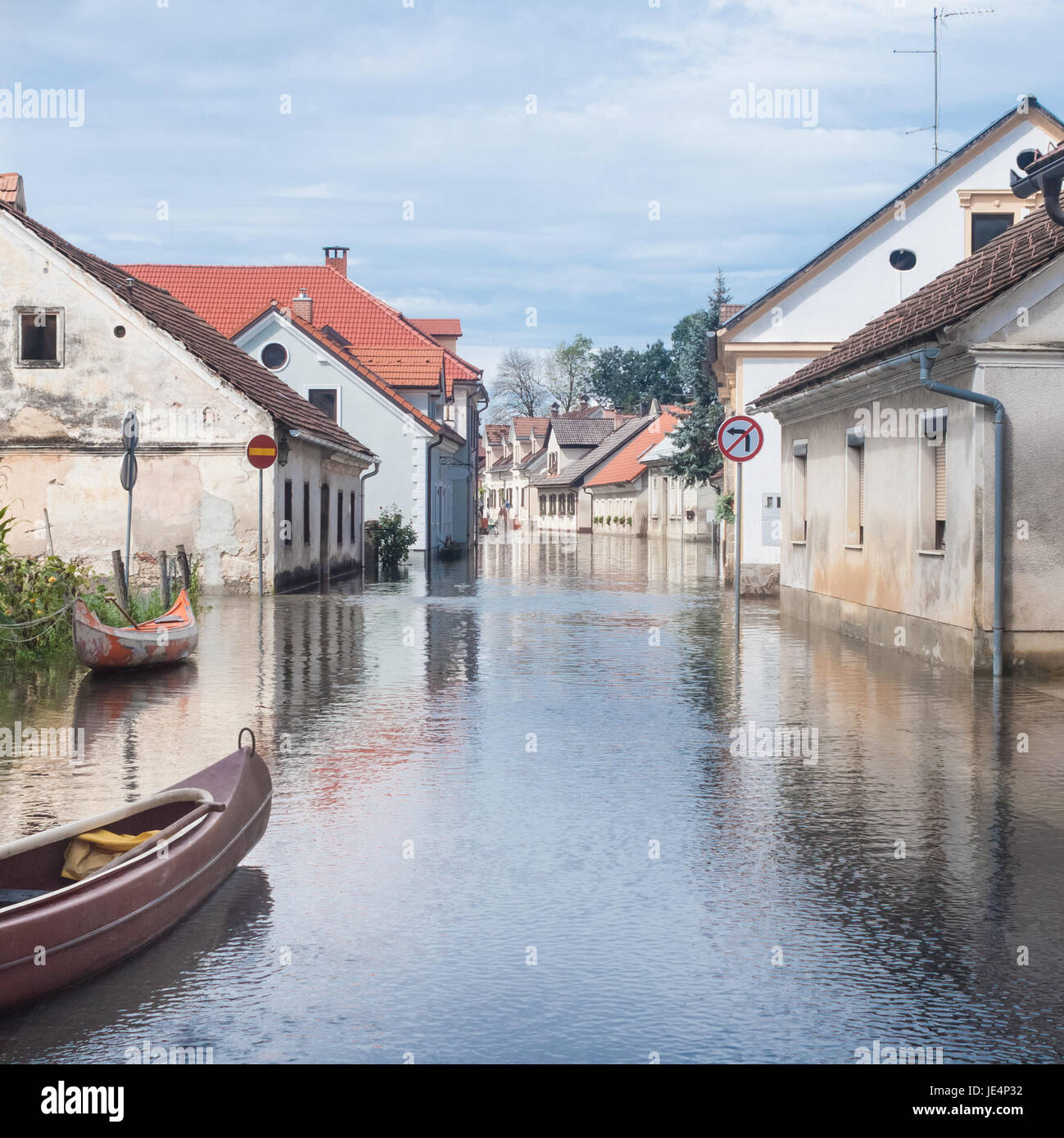 Rural village houses in floodwater. Road with the river overflown with ...