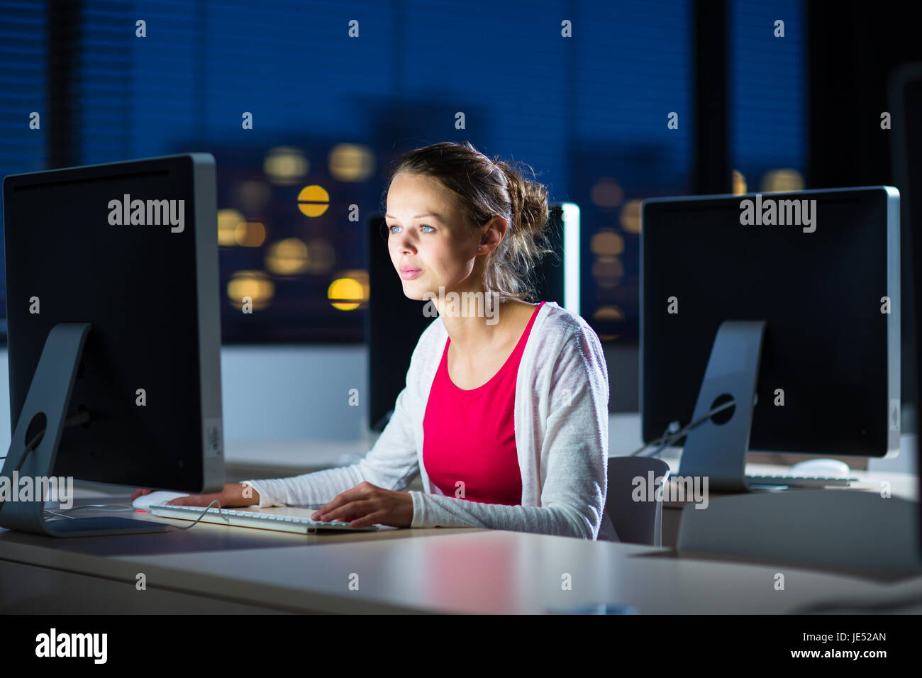 Pretty, young female college student using a desktop computer/pc in a ...