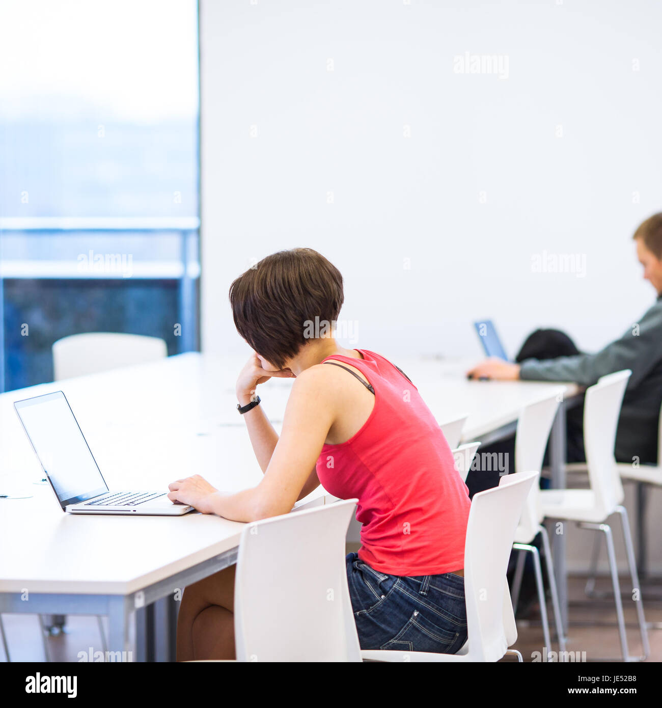 Pretty, young college student studying in the library/a study room at ...