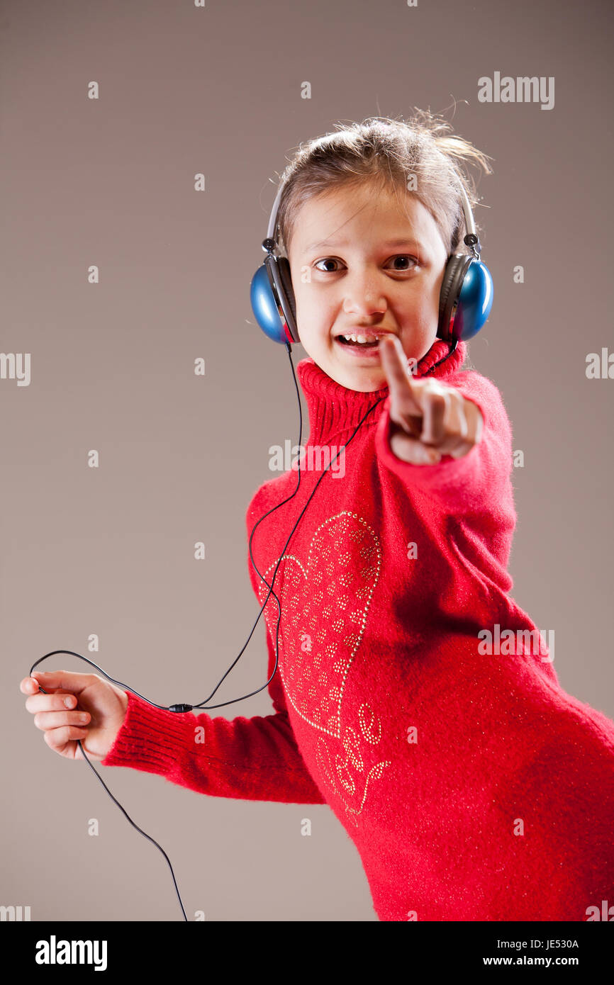 Little girl dancing and pointing her finger to you while listening to ...