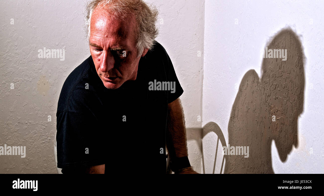 An older white man sitting in a corner looking away with shadow Stock ...