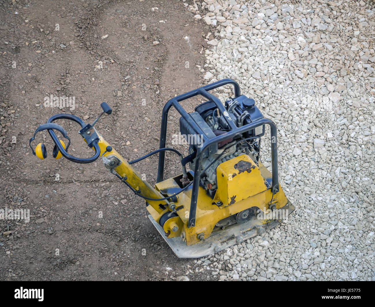 Old yellow plate compactor on aggregate bed Stock Photo - Alamy