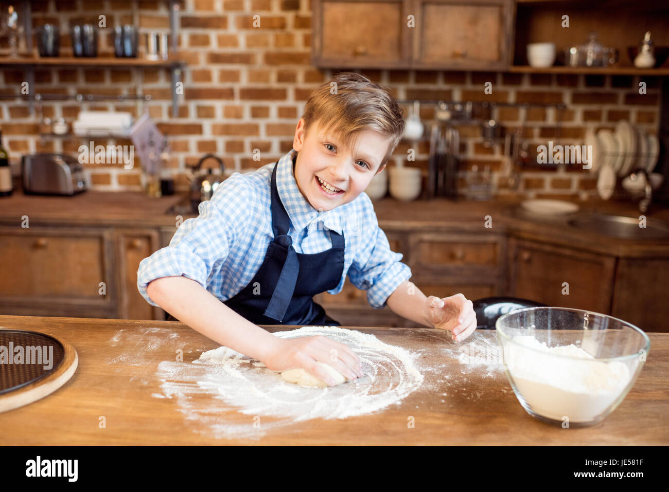 little boy making pizza dough on wooden tabletop in kitchen Stock Photo ...