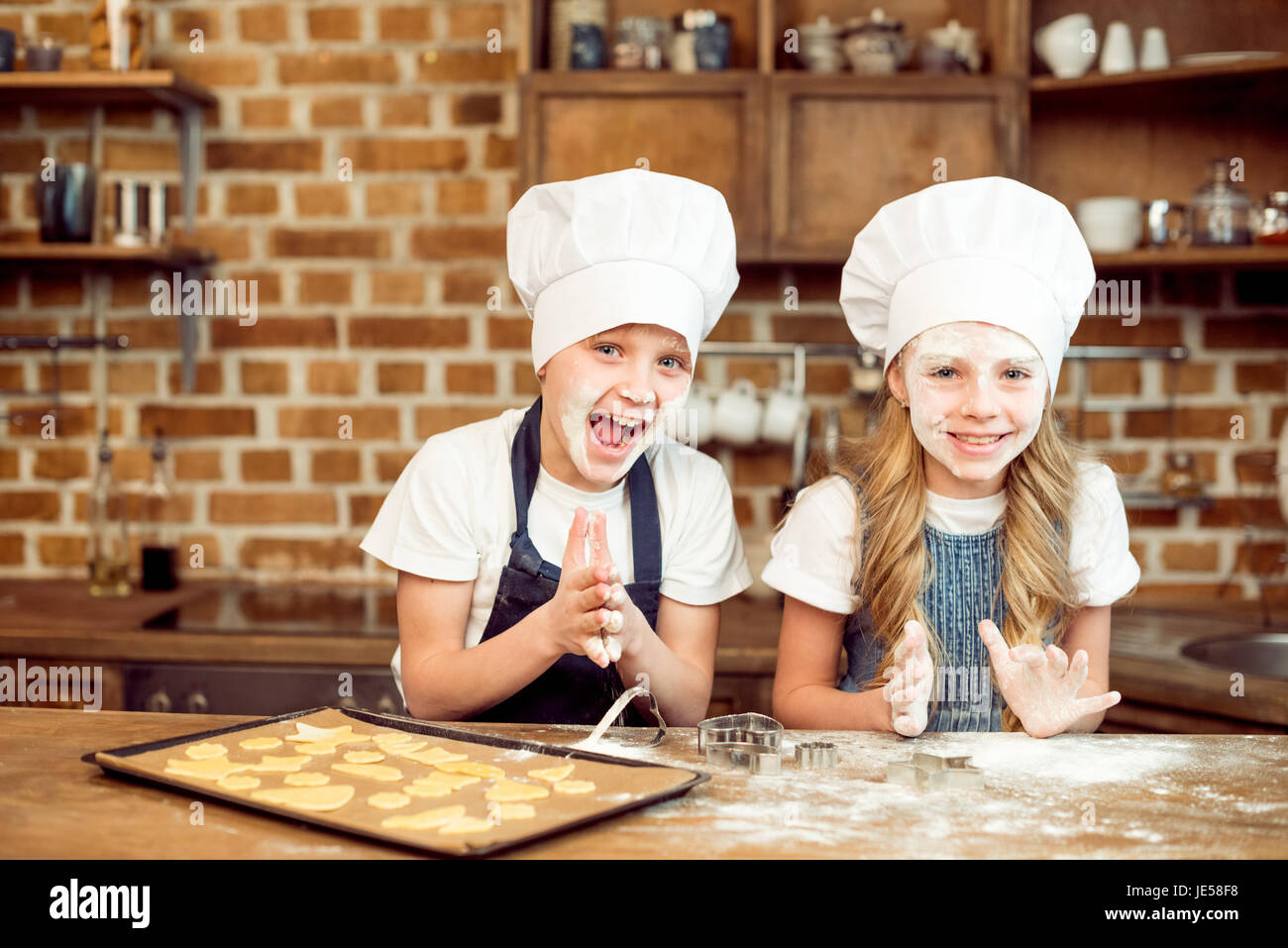 little boy and girl playing with flour while making shaped cookies ...