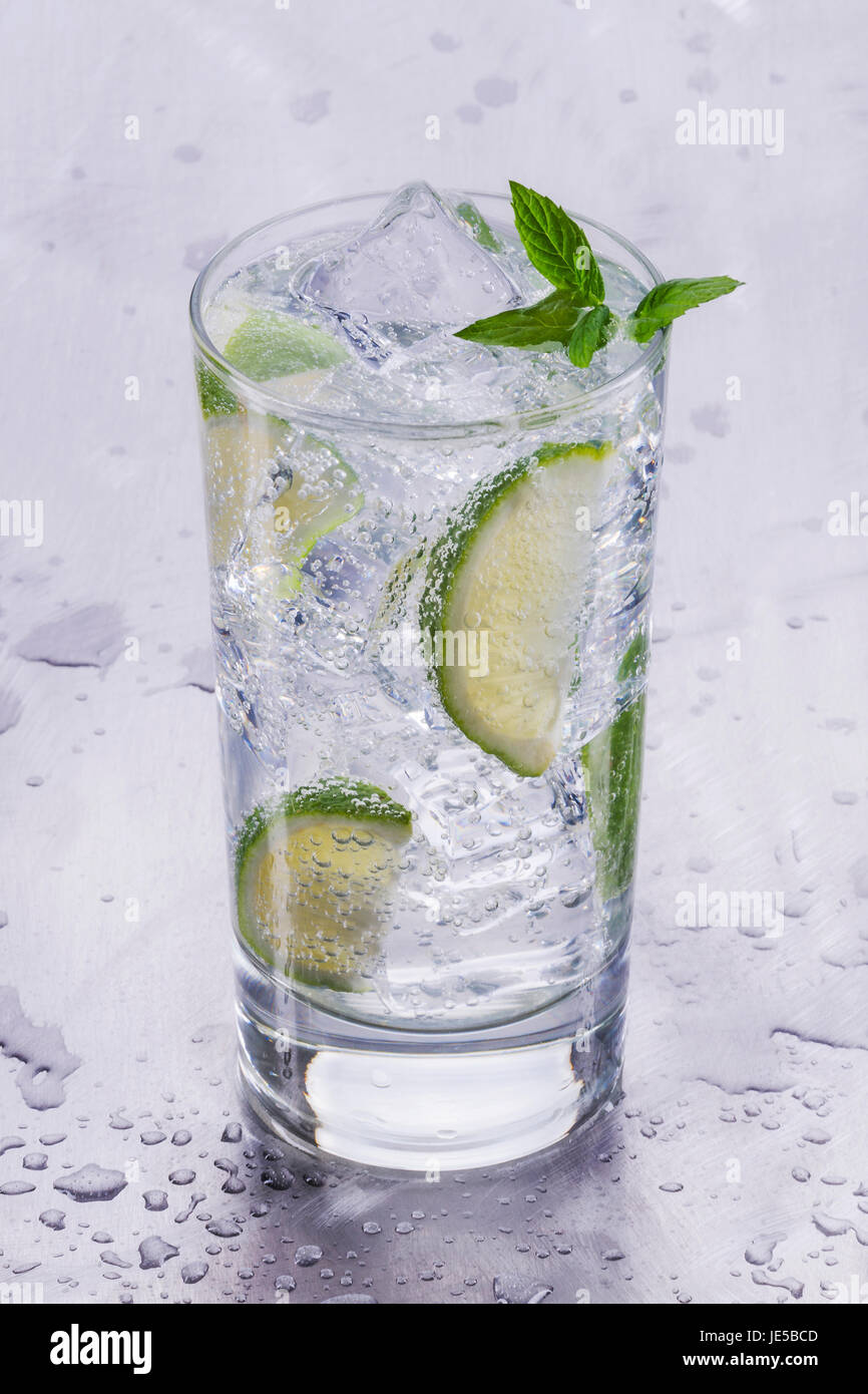 Glass of refreshing cold mineral water with pieces of lime Stock Photo ...