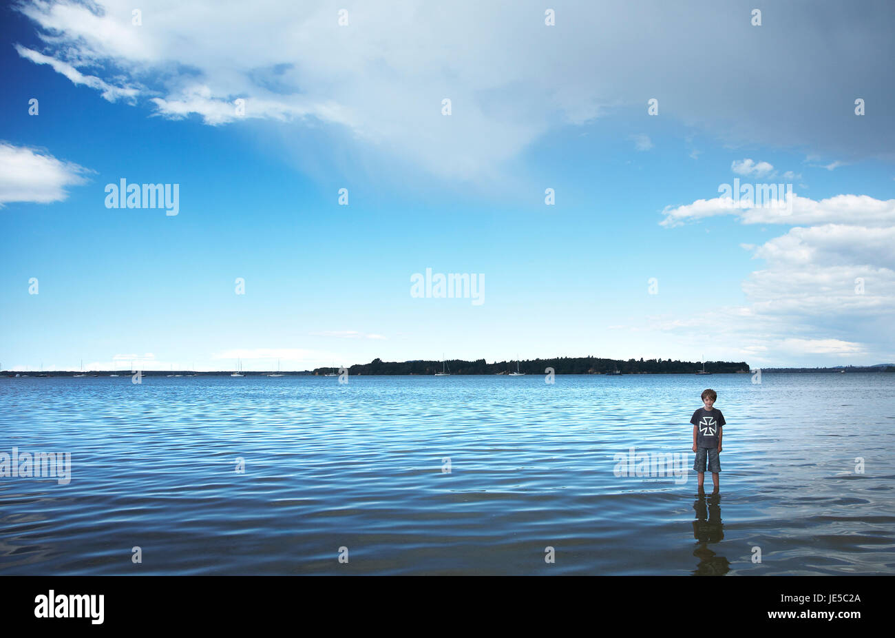 Boy standing in shallow water cooney reserve, omokoroa looking over ...
