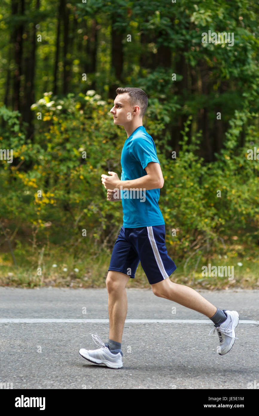 Young boy running outdoor through the forest on a road Stock Photo - Alamy