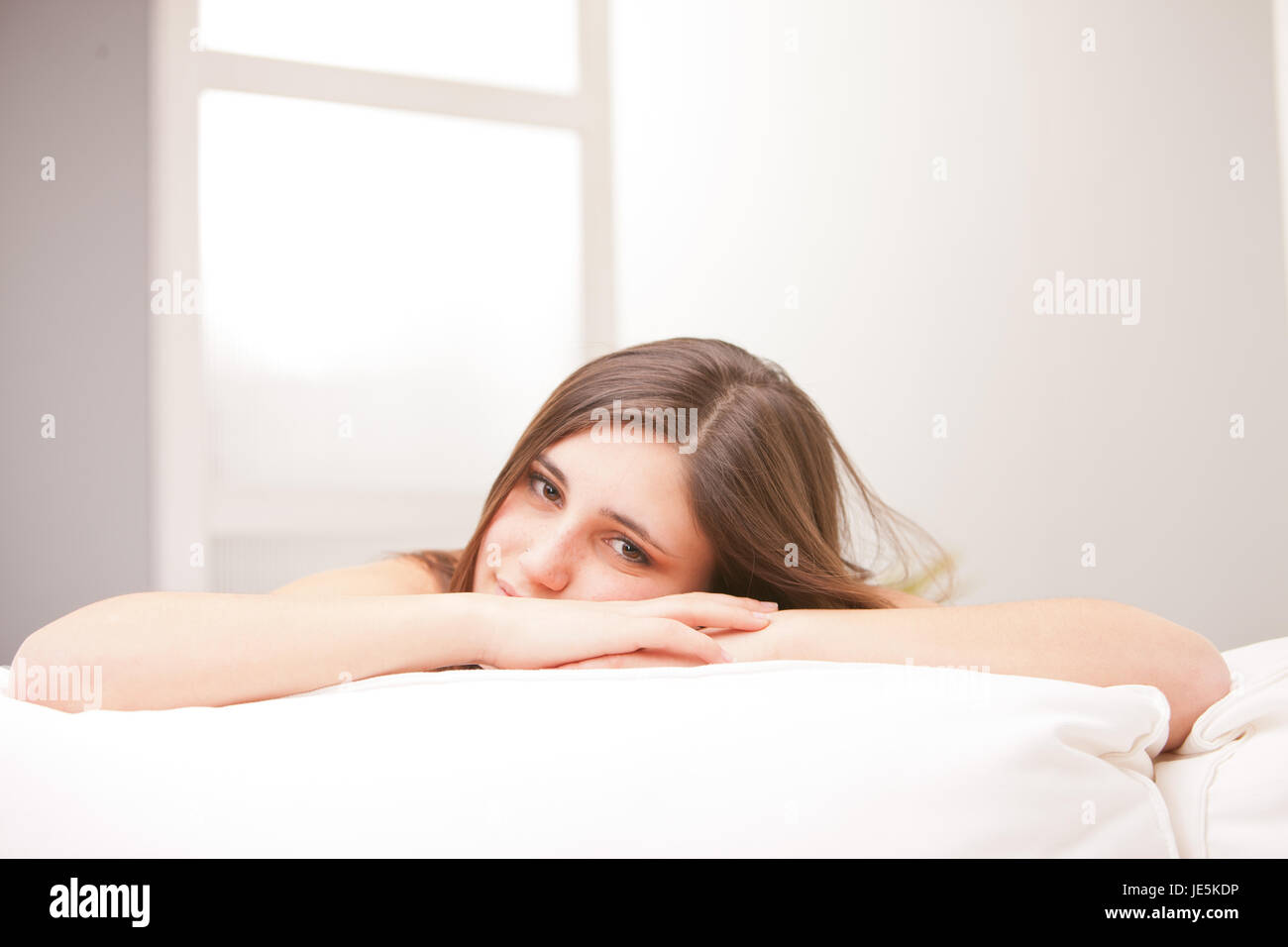 beautiful girl laying down on the sofa resting on her arms with a sweet ...