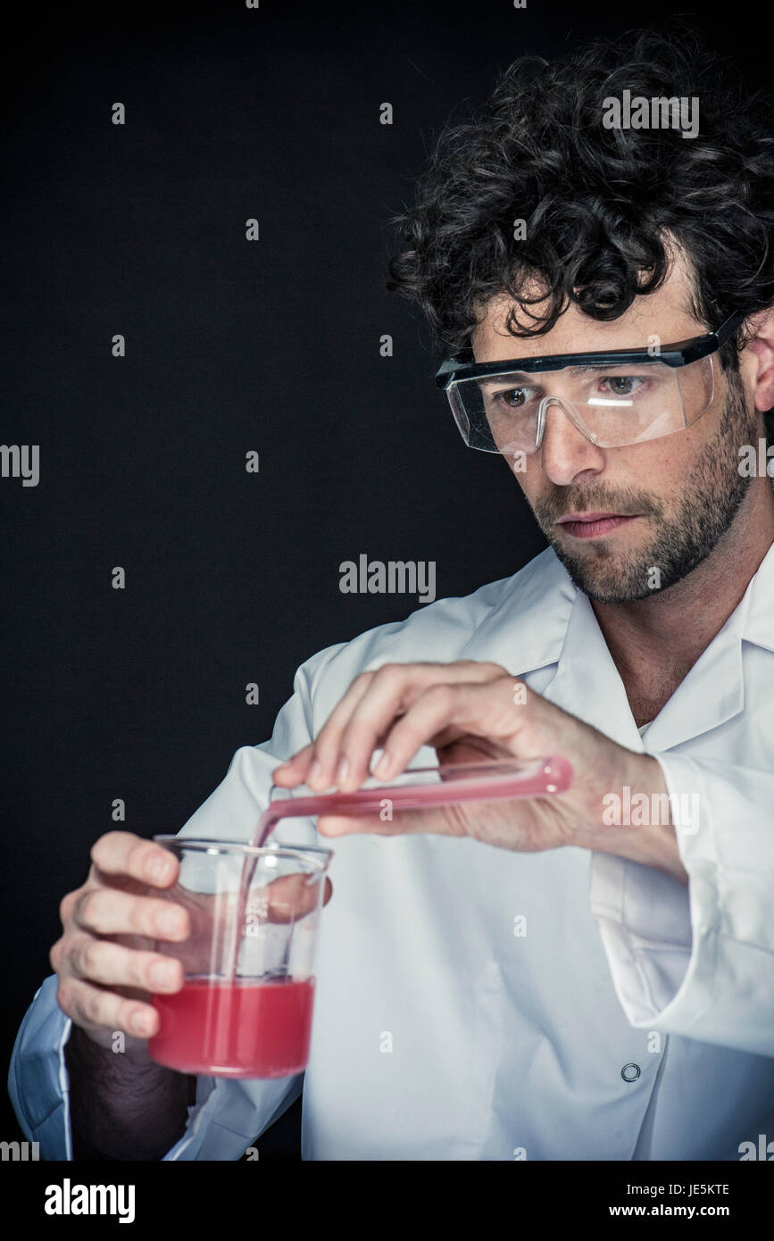 Chemist pouring liquid from test tube into beaker Stock Photo - Alamy