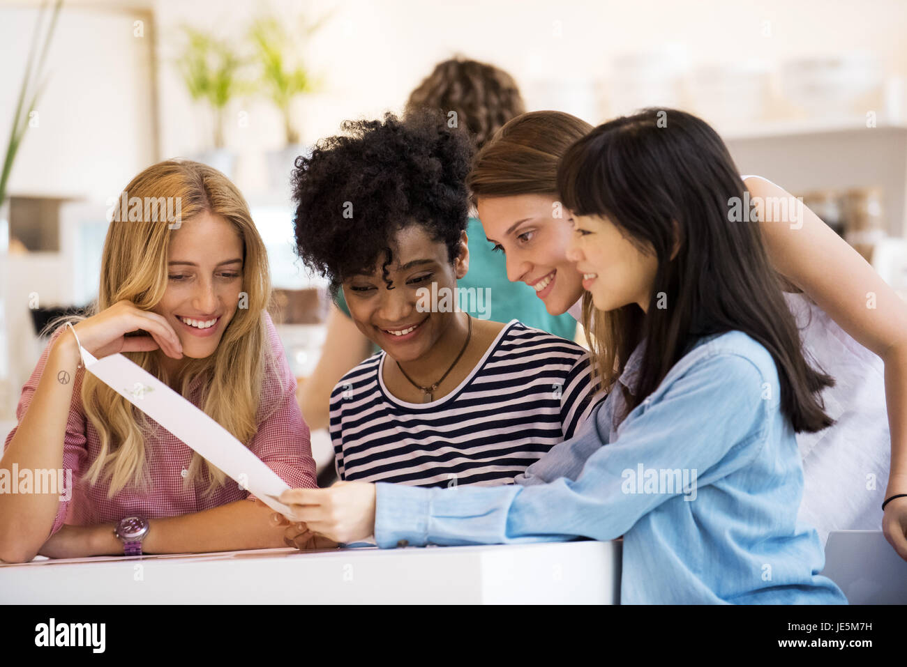 Group of friends looking at menu together in cafe Stock Photo - Alamy