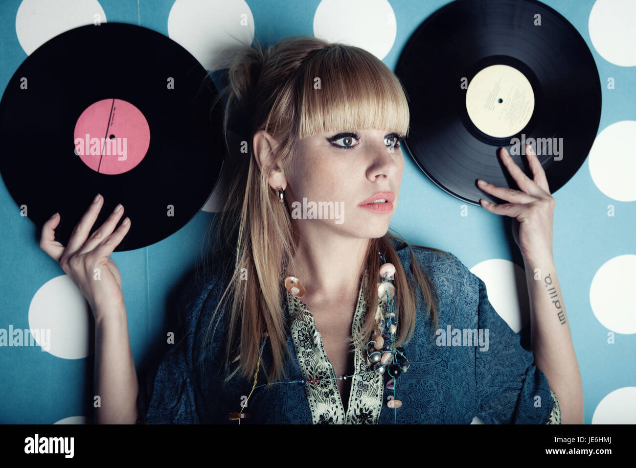 Portrait of a young beautiful blonde woman with vinyl records in hands ...