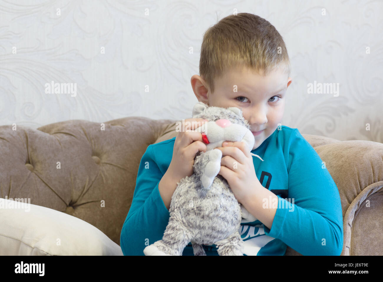boy embraces plush toy sitting on the couch Stock Photo - Alamy