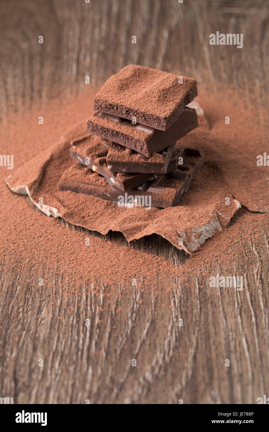 Pyramid of milk chocolate sprinkled with cocoa powder on wooden table ...