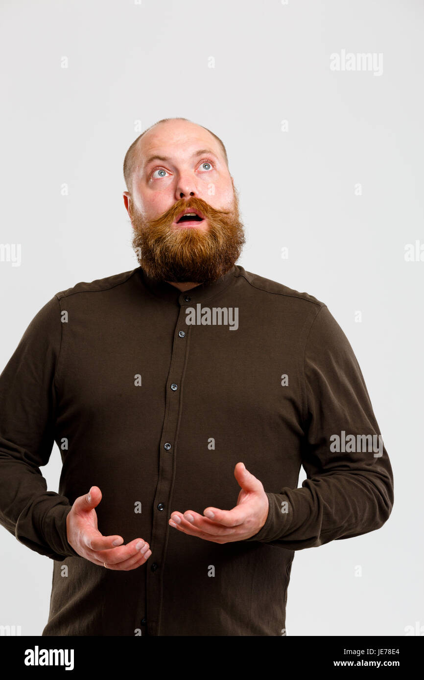 Man with ginger beard looks up on empty isolated background, place for ...