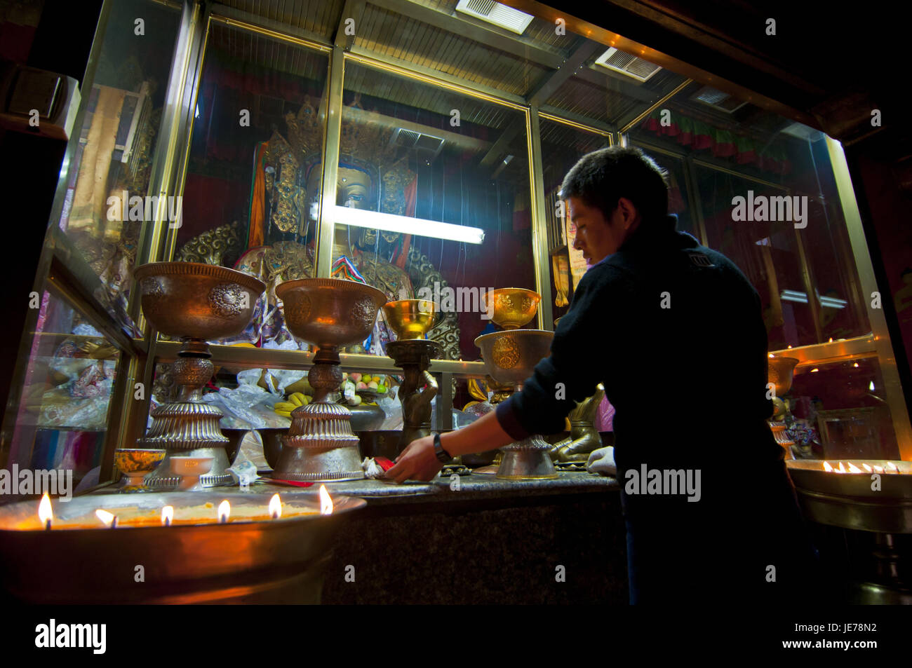 Monk before a Buddha statue behind skyers in the Ramoche temple, Lhasa ...