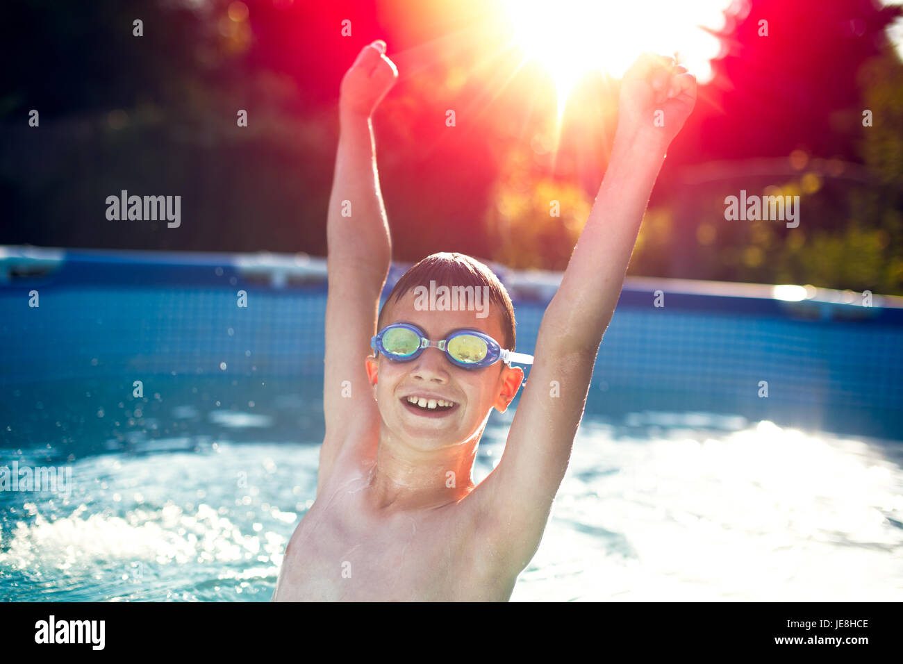 Happy kid enjoying summer sunset in swimming pool in sunset, hands up ...