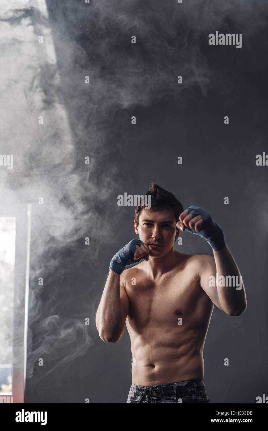 Handsome man in the rays of the sun and smoke boxing in gym Stock Photo ...