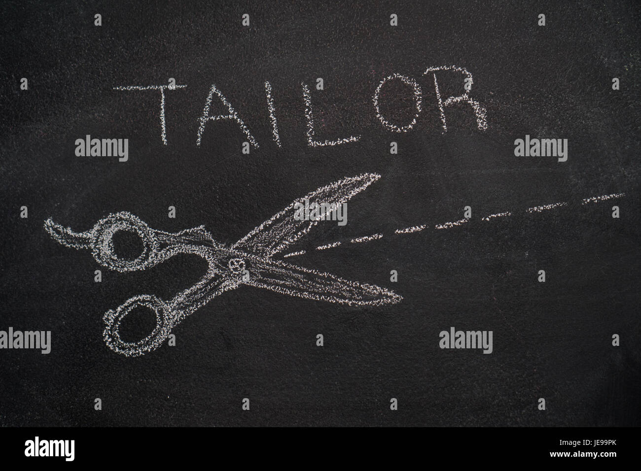 Scissors with cut line and tailor word drawn with white chalk on ...