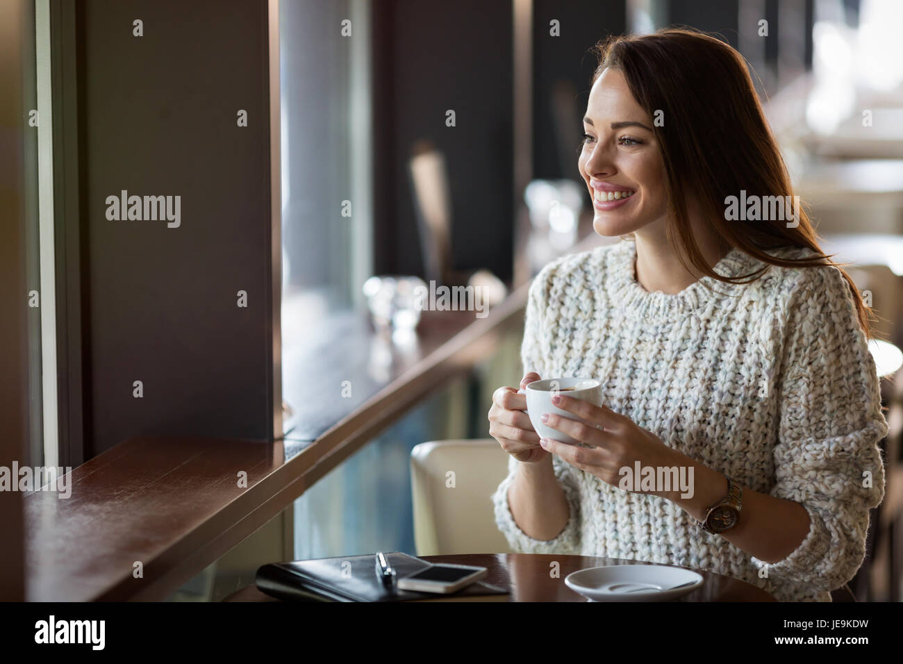 Beautiful woman drinking coffee in restaurant alone Stock Photo - Alamy