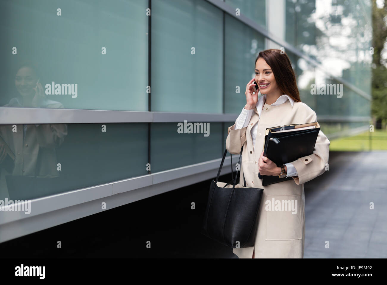 Attractive businesswoman standing and taking call Stock Photo - Alamy