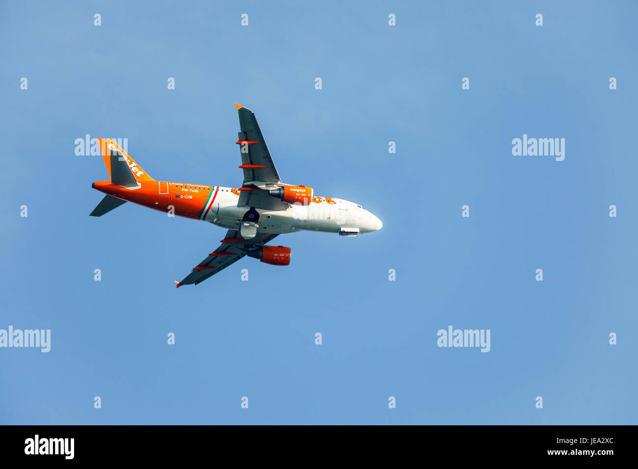 Orange and white EasyJet Airbus A319 in flight, cloudless clear blue ...