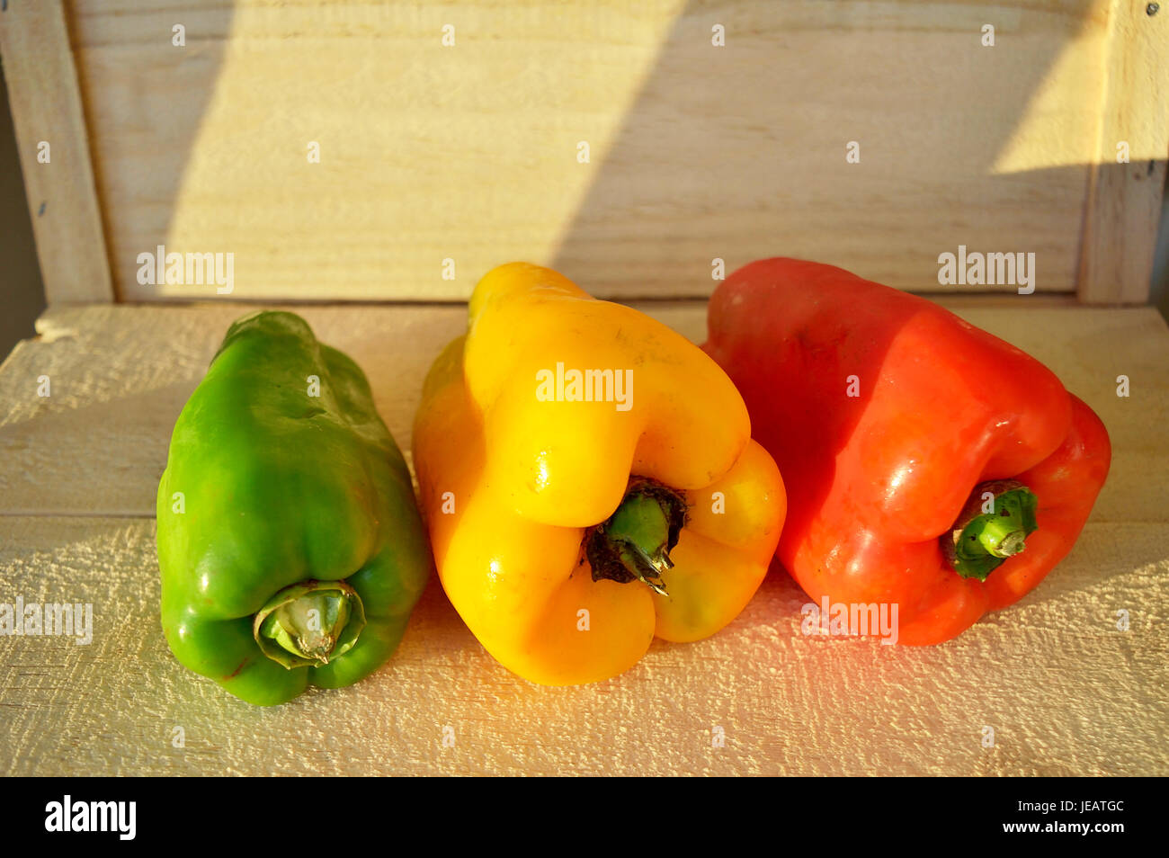 Three Bell Peppers over a wood box illuminated by the sunset light ...