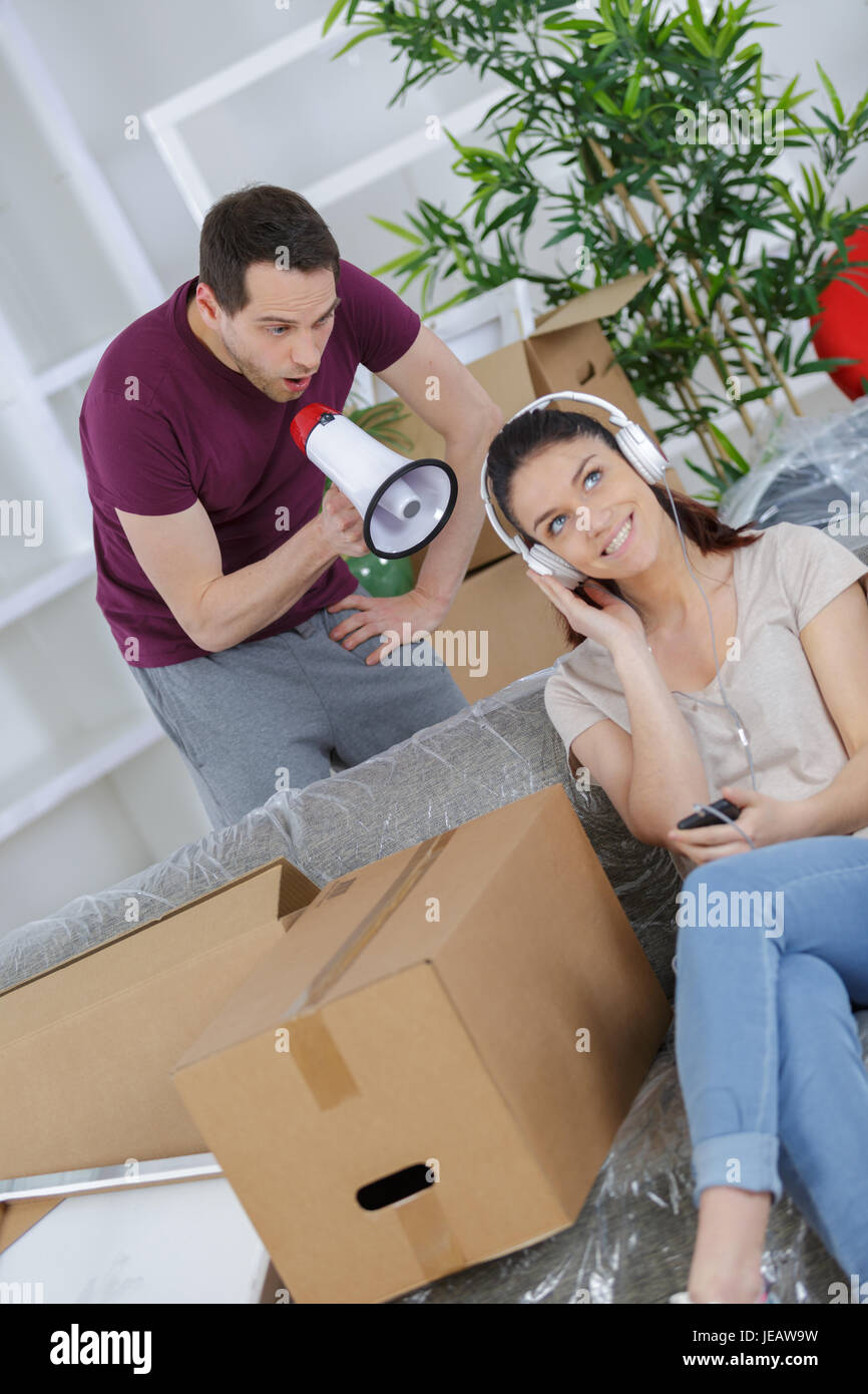 busy man packing books and lazy wife on couch Stock Photo - Alamy