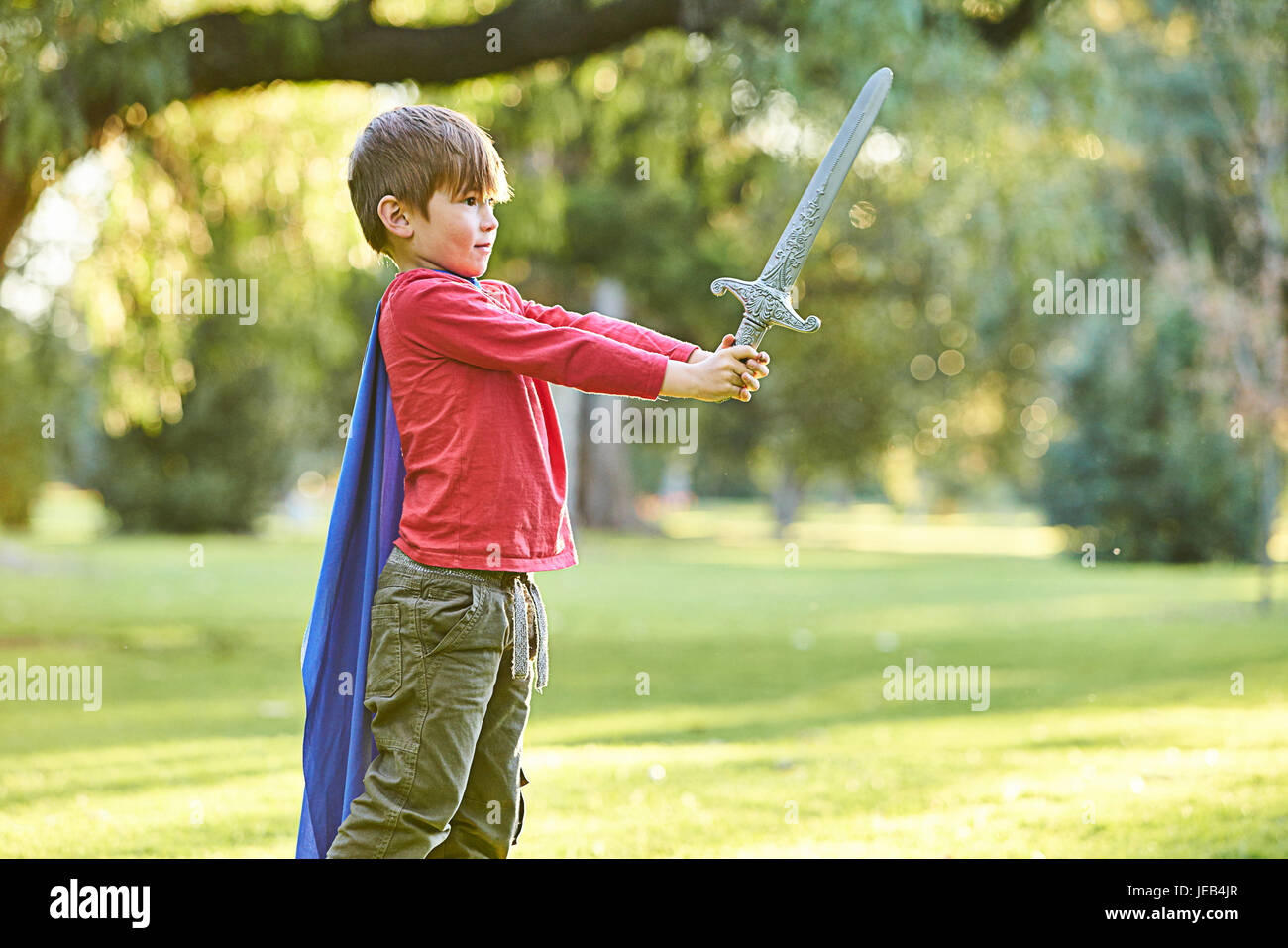 young boy playing in park with toy sword Stock Photo - Alamy