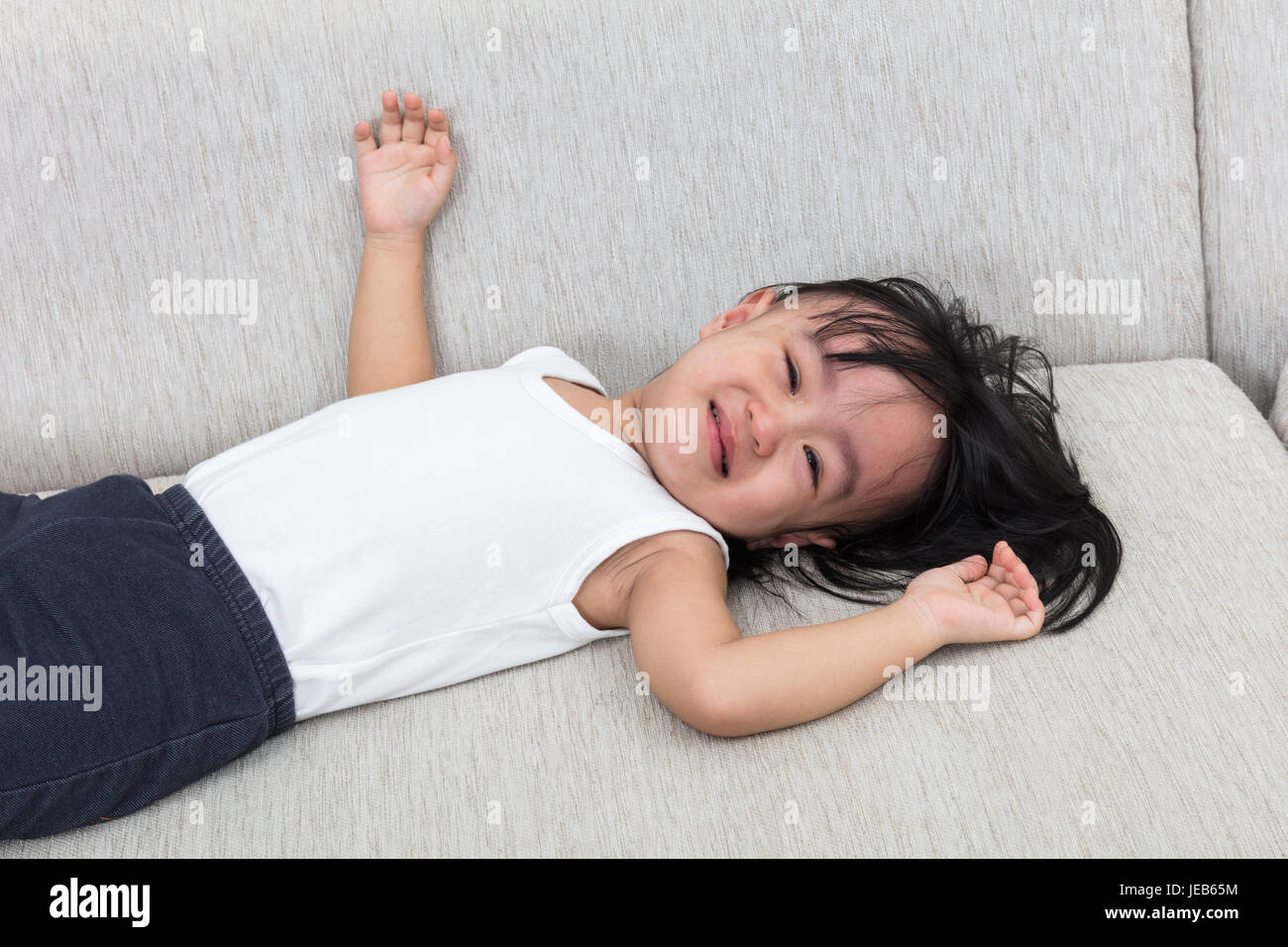 Asian Chinese little girl crying on the sofa in the living room at home ...
